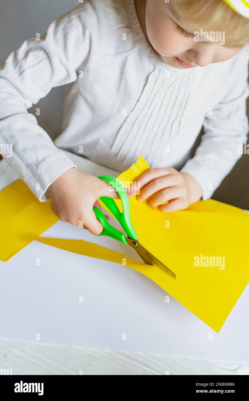 Cute little girl cutting paper shapes in kindergarten. child makes ...