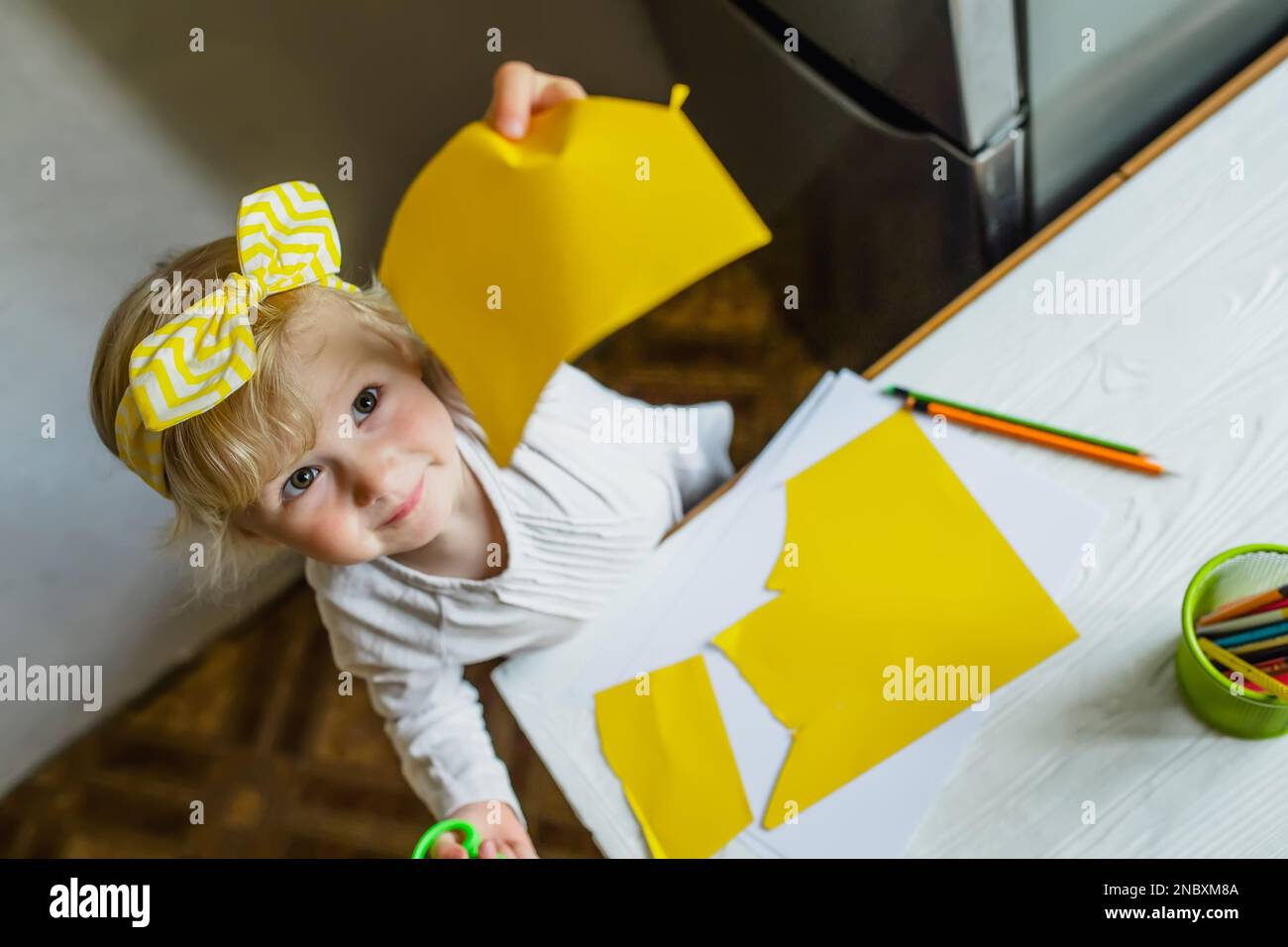 little girl shows a paper-cut figure. child makes applications from ...