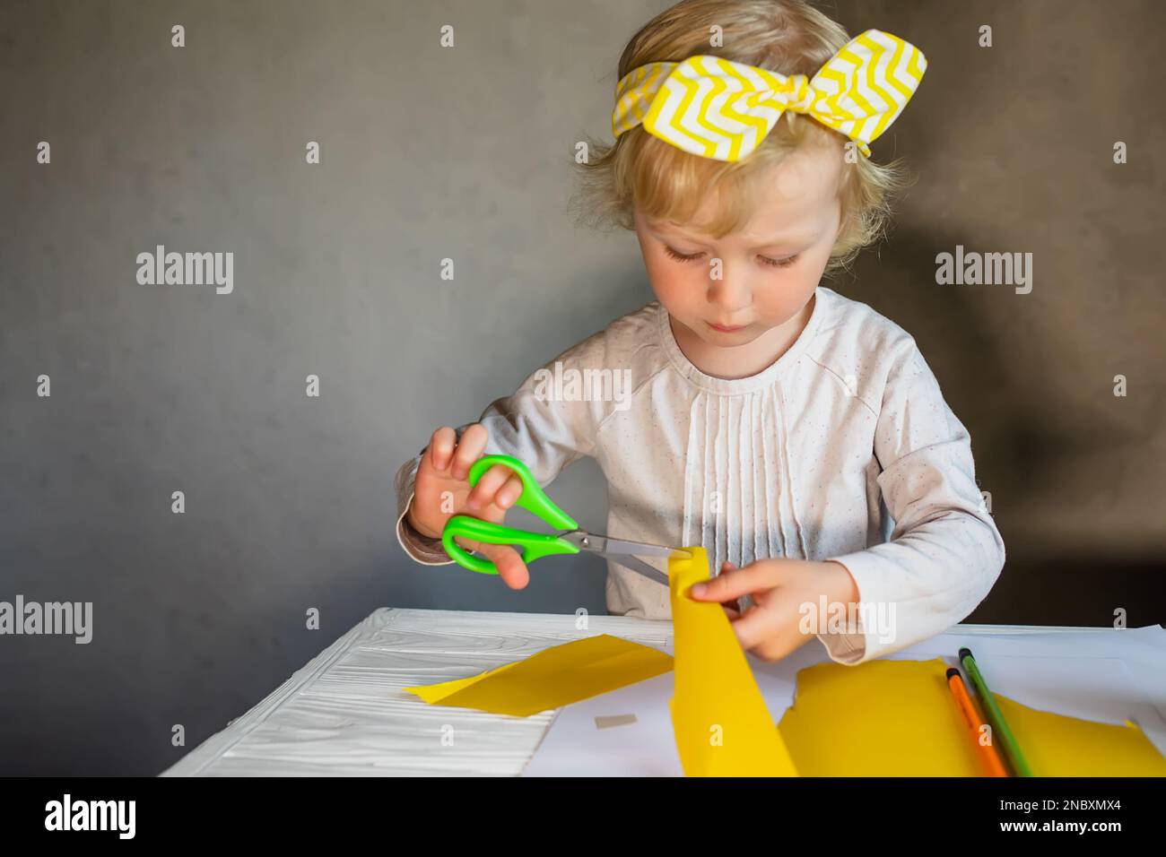 girl cuts out ornaments from colorful paper for crafting. Fine motor ...
