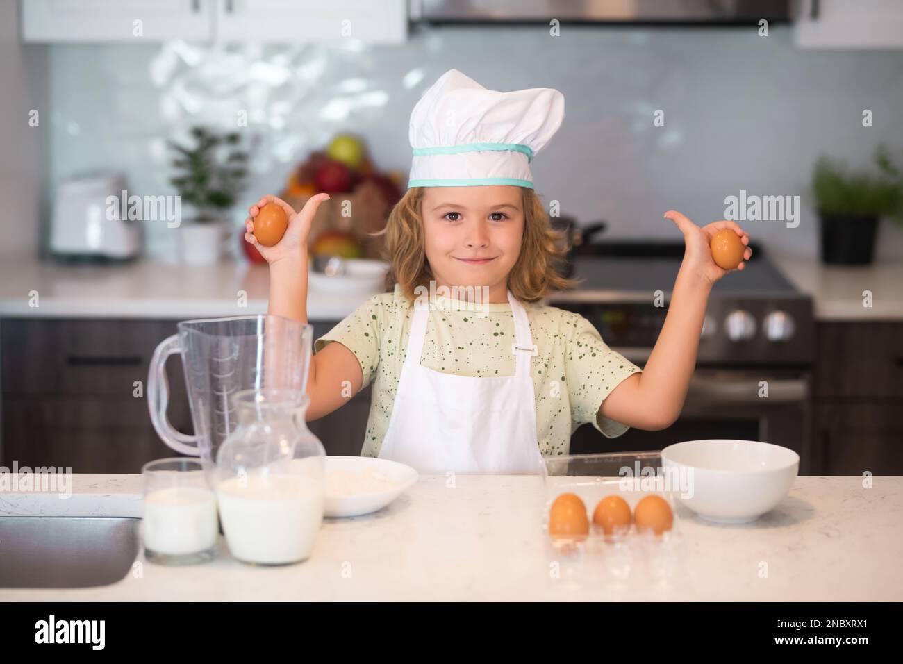 Kid chef cook with eggs at kitchen. Chef kid boy baking on the kitchen ...