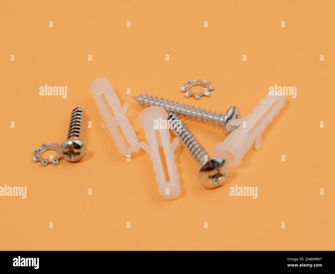 Screws and plastic dowels on an orange background. Bolts and dowels ...