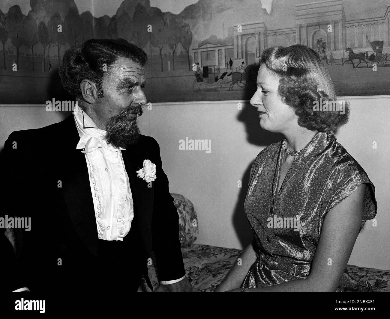 Emlyn Williams, the actor, in character costume, chats with Monica ...