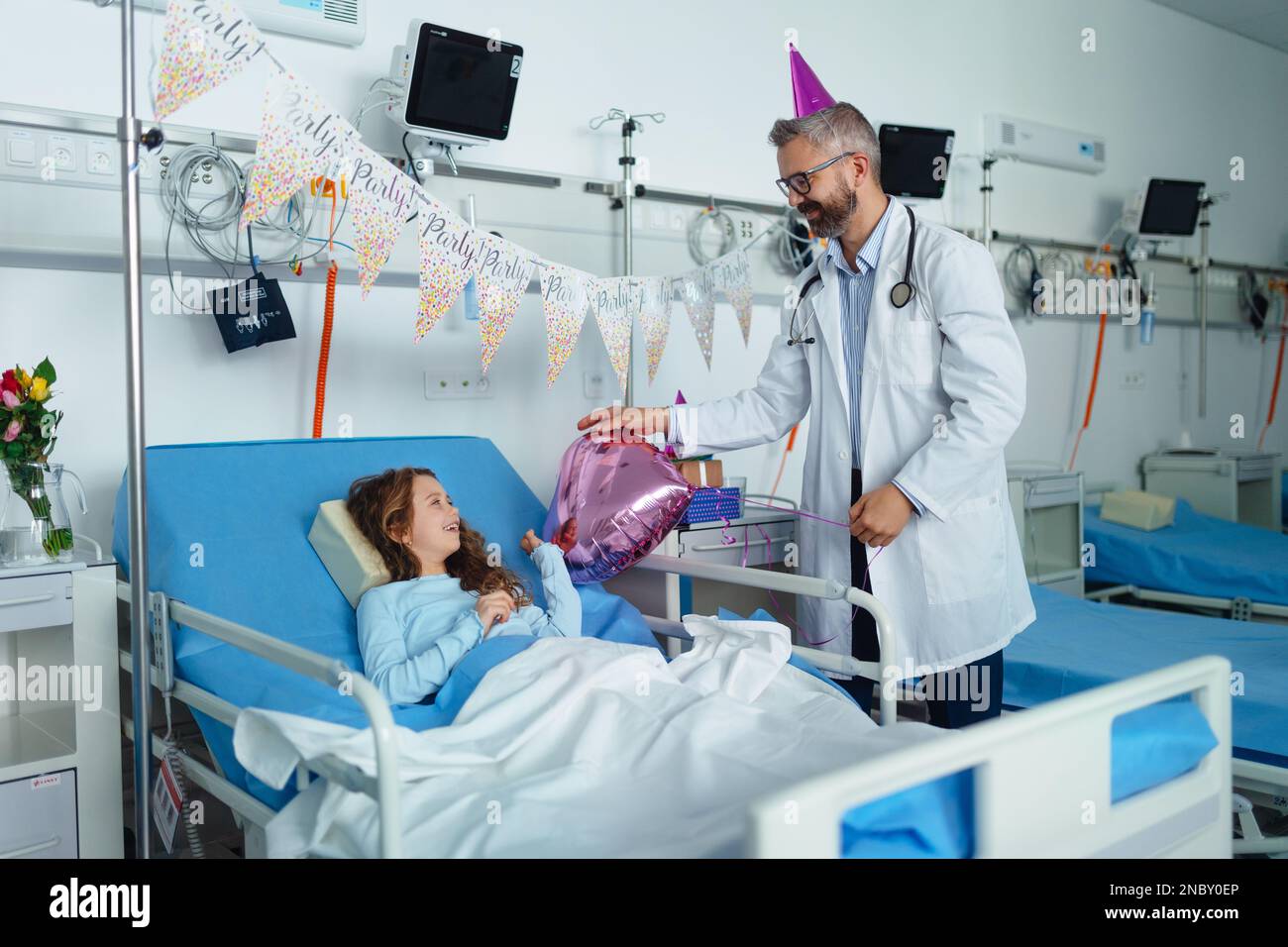 Happy doctor celebrating birthday with little girl in hospital room ...