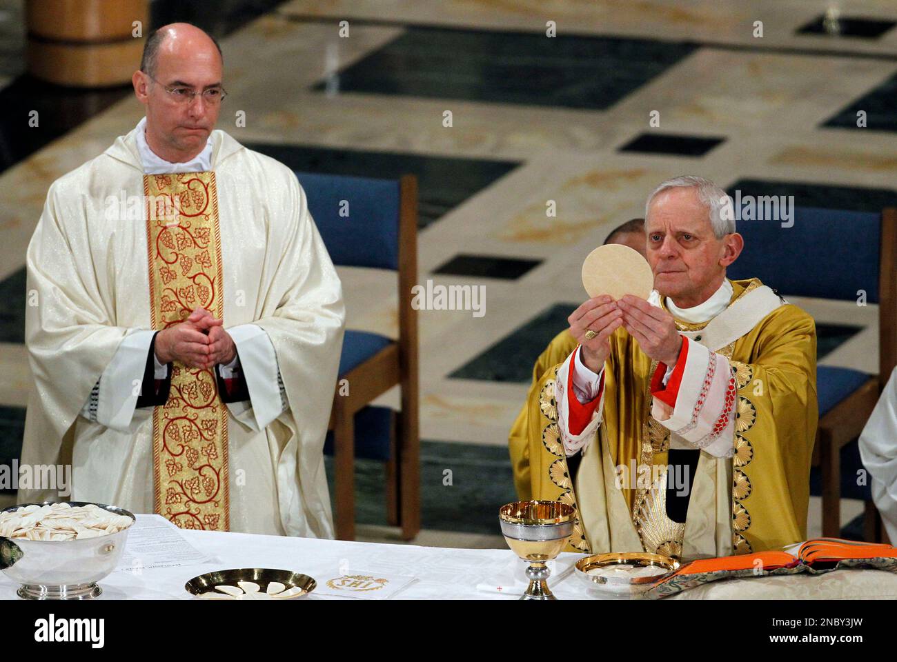 Cardinal Donald Wuerl, right, Archbishop of Washington, holds the Host ...