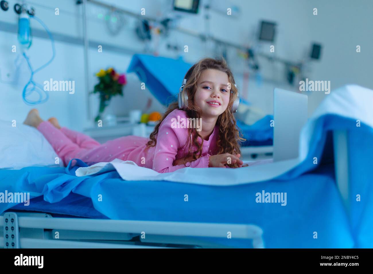Little sick girl lying at hospital bed and using laptop Stock Photo - Alamy