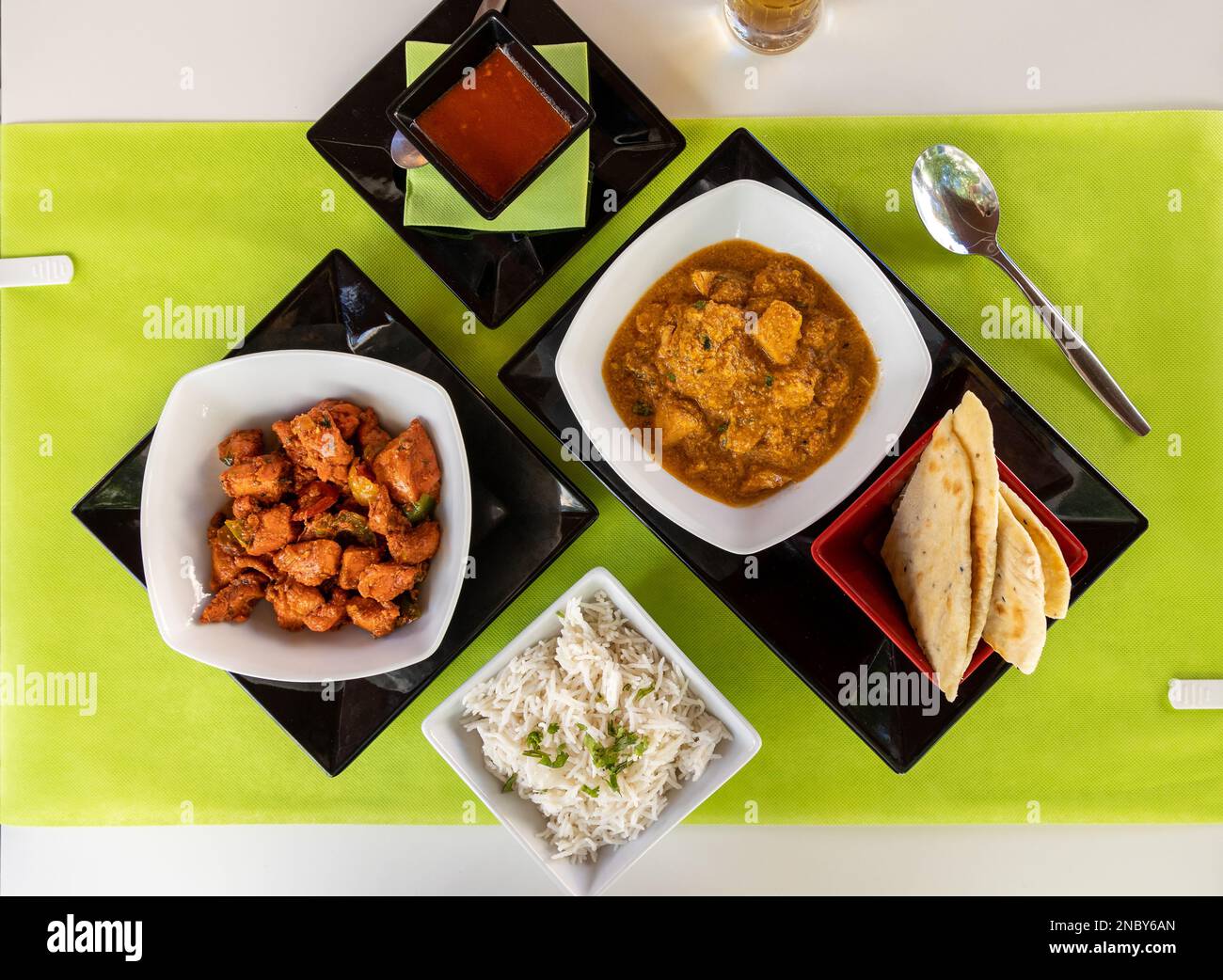 A top view of different Indian dishes on white table with green ...