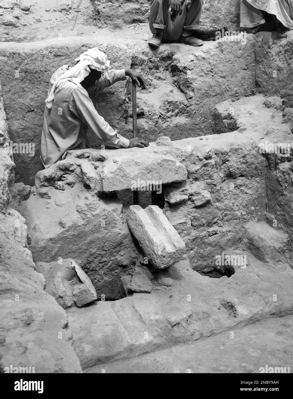 A Bahraini workman excavates the cistern behind a toilet room in a ...