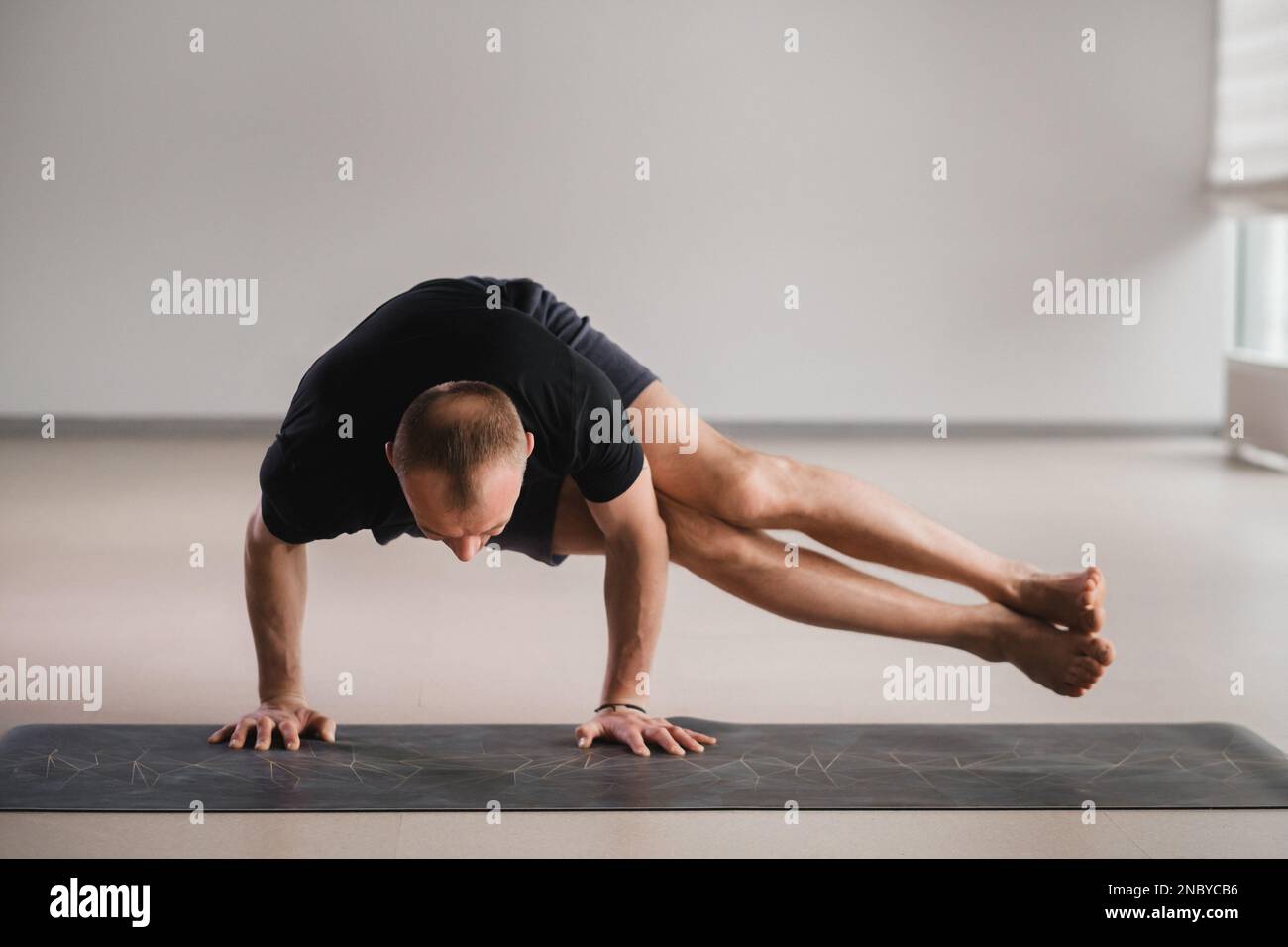 An athletically built man does yoga in the gym on a mat Stock Photo - Alamy