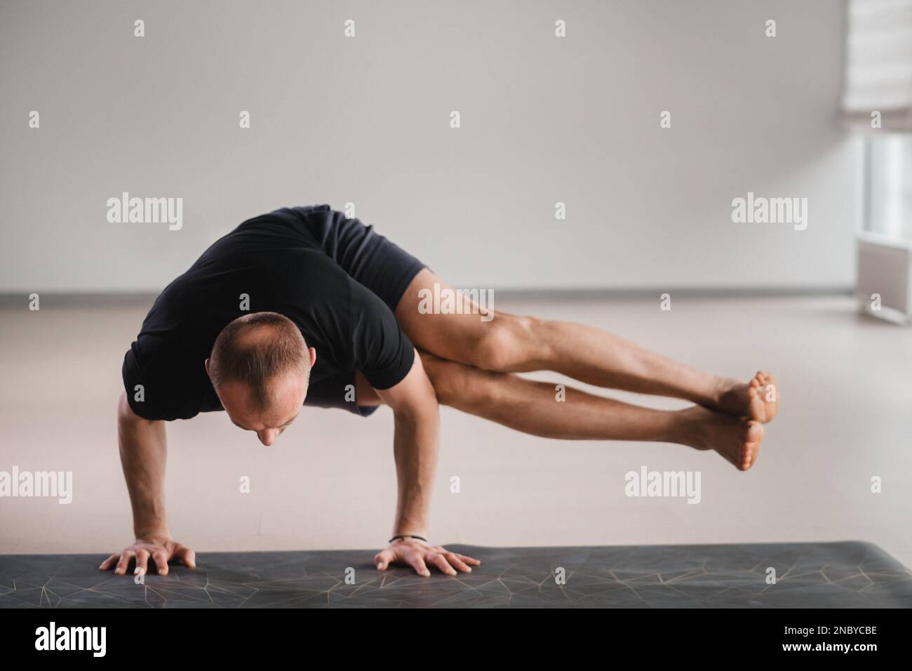 An athletically built man does yoga in the gym on a mat Stock Photo - Alamy