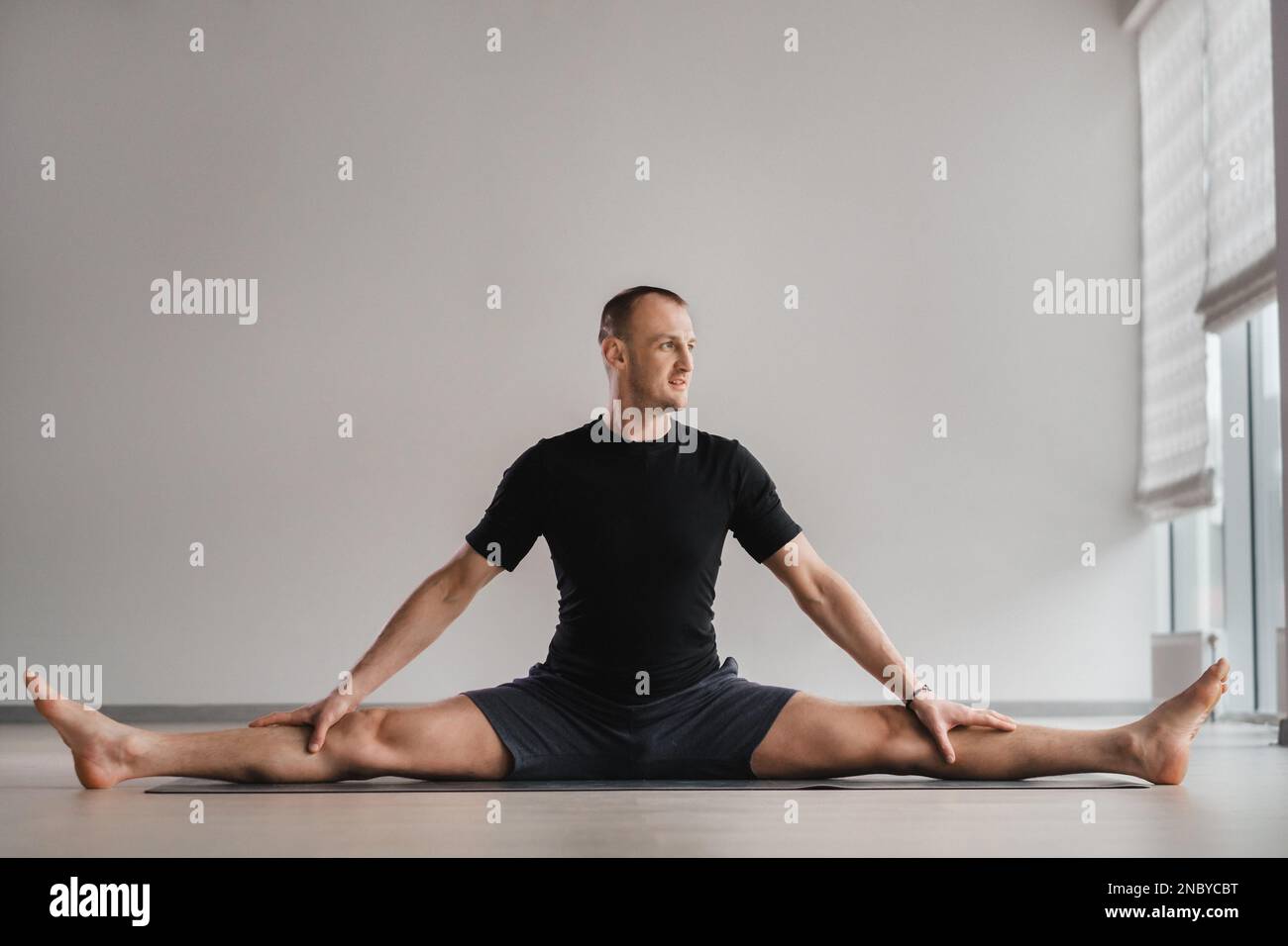 An athletically built man does yoga in the gym on a mat Stock Photo - Alamy