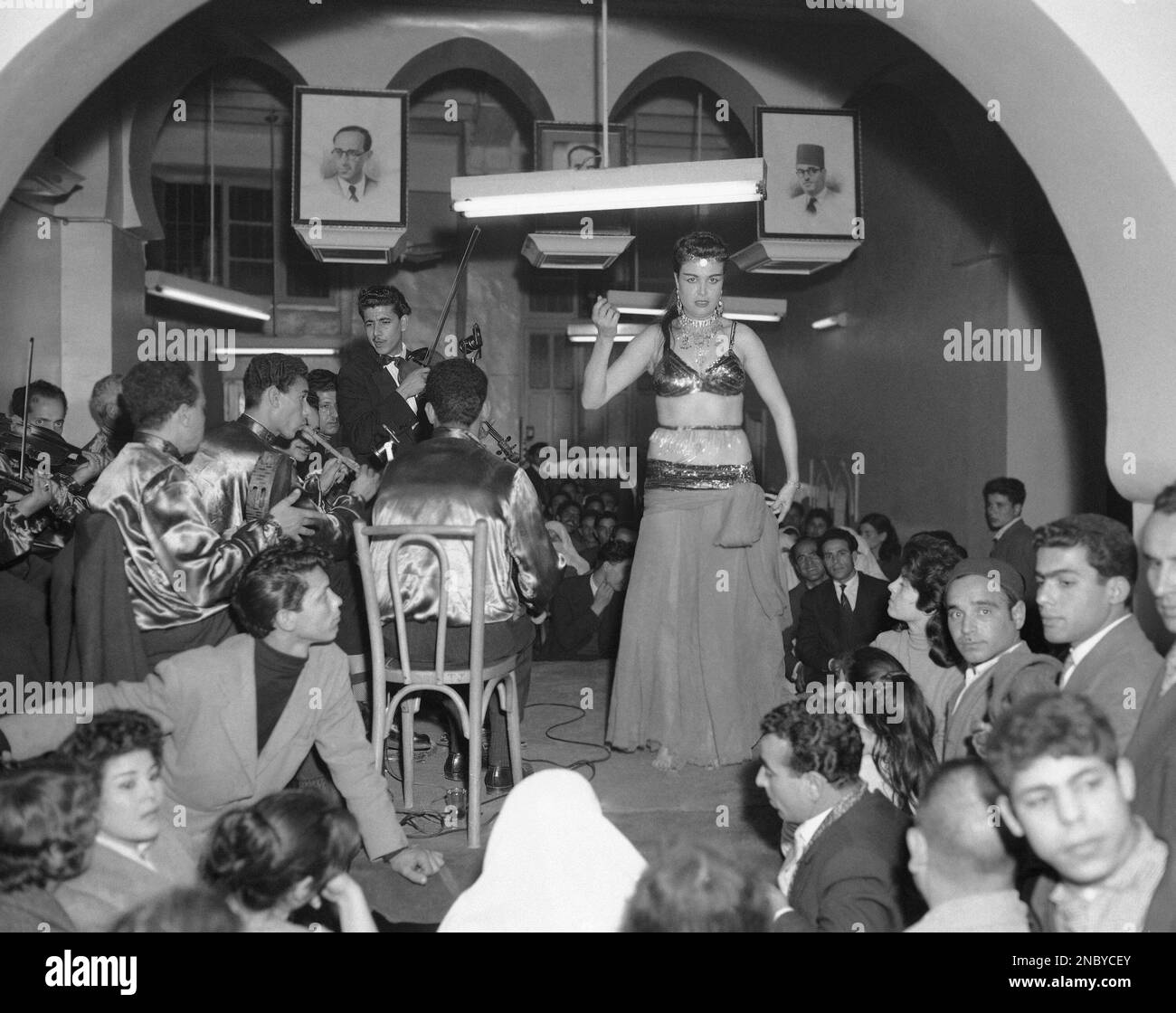 A belly dancer is entertaining a crowd of customers in a night club in ...