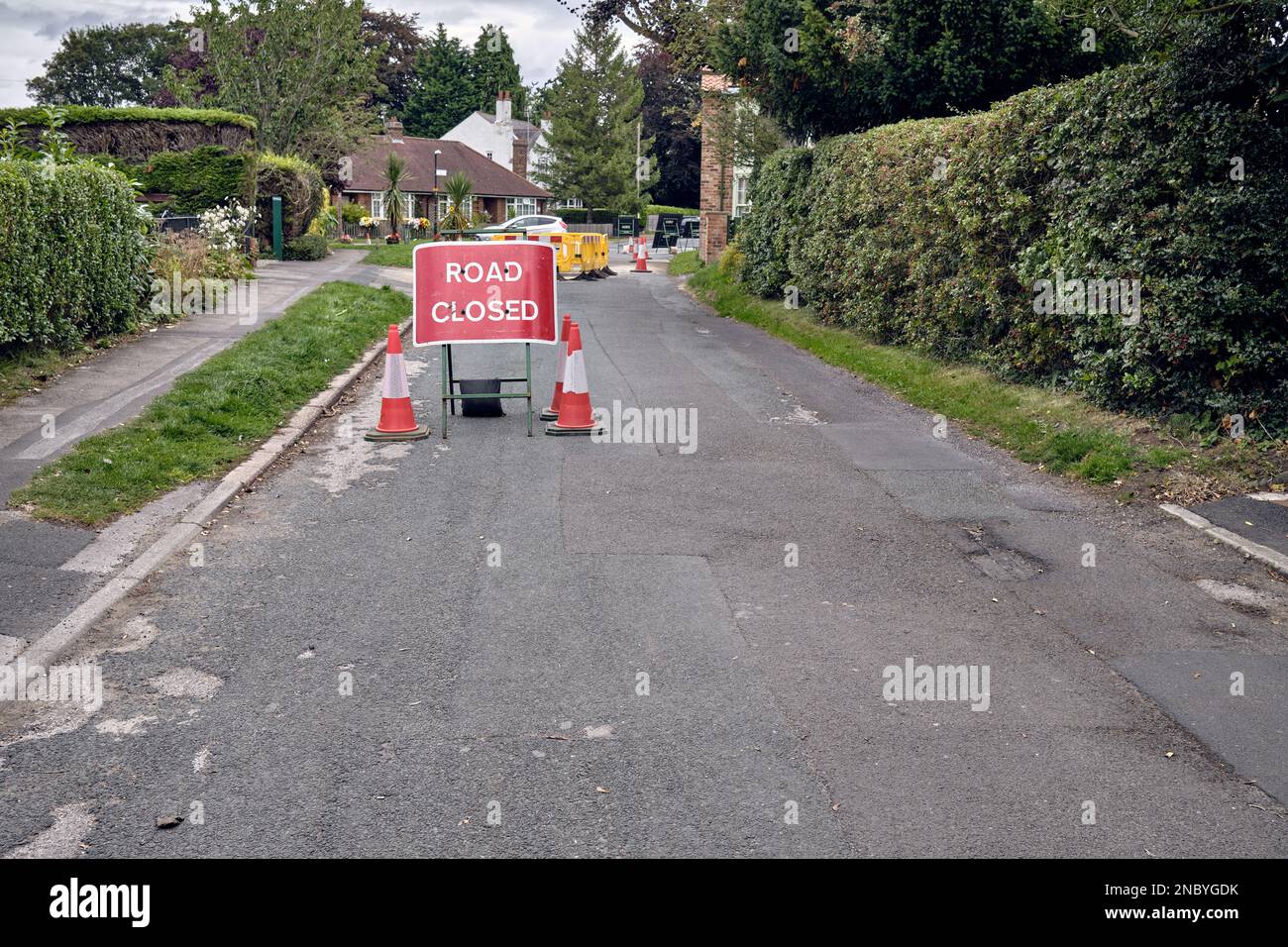 A road closed sign on a suburban British street. Yellow barriers ...