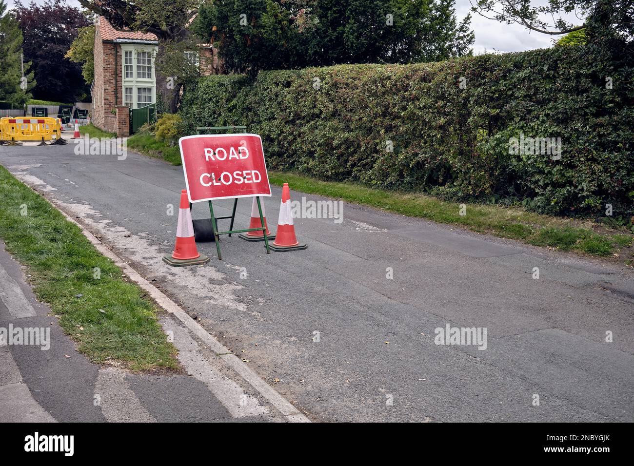 A road closed sign on a suburban British street. Yellow barriers ...