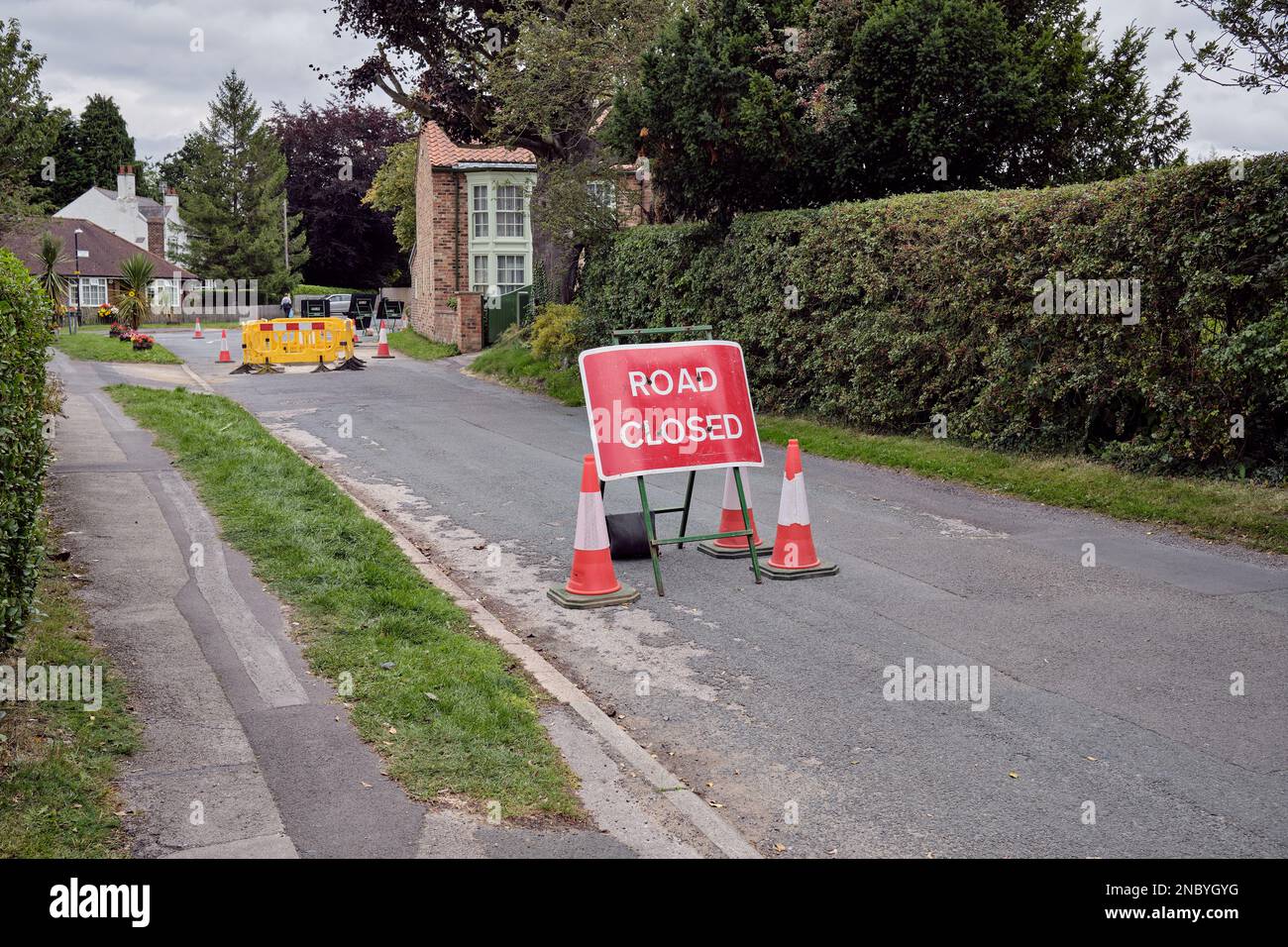 A road closed sign on a suburban British street. Yellow barriers ...