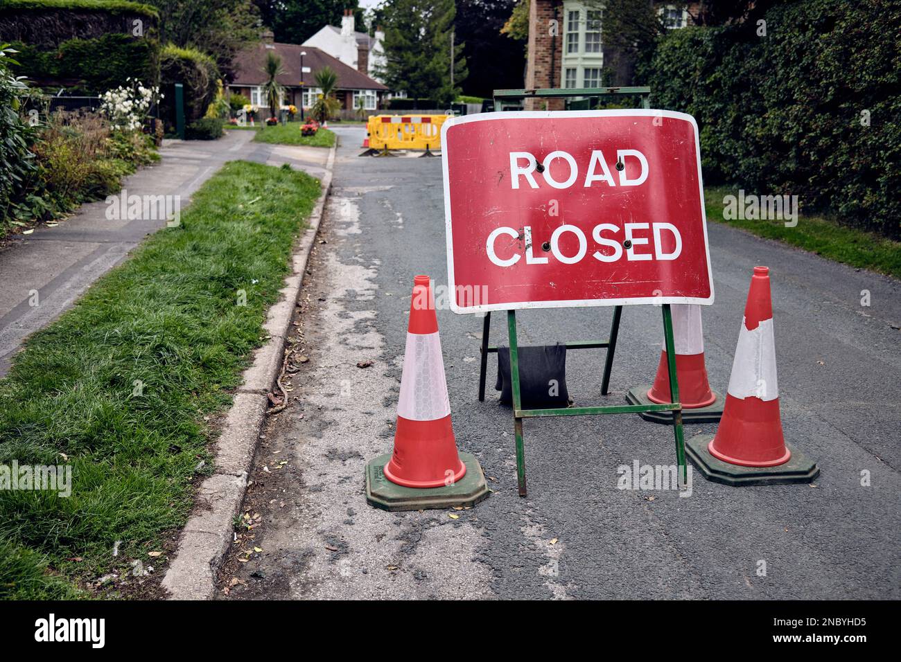 A road closed sign on a suburban British street. Yellow barriers ...