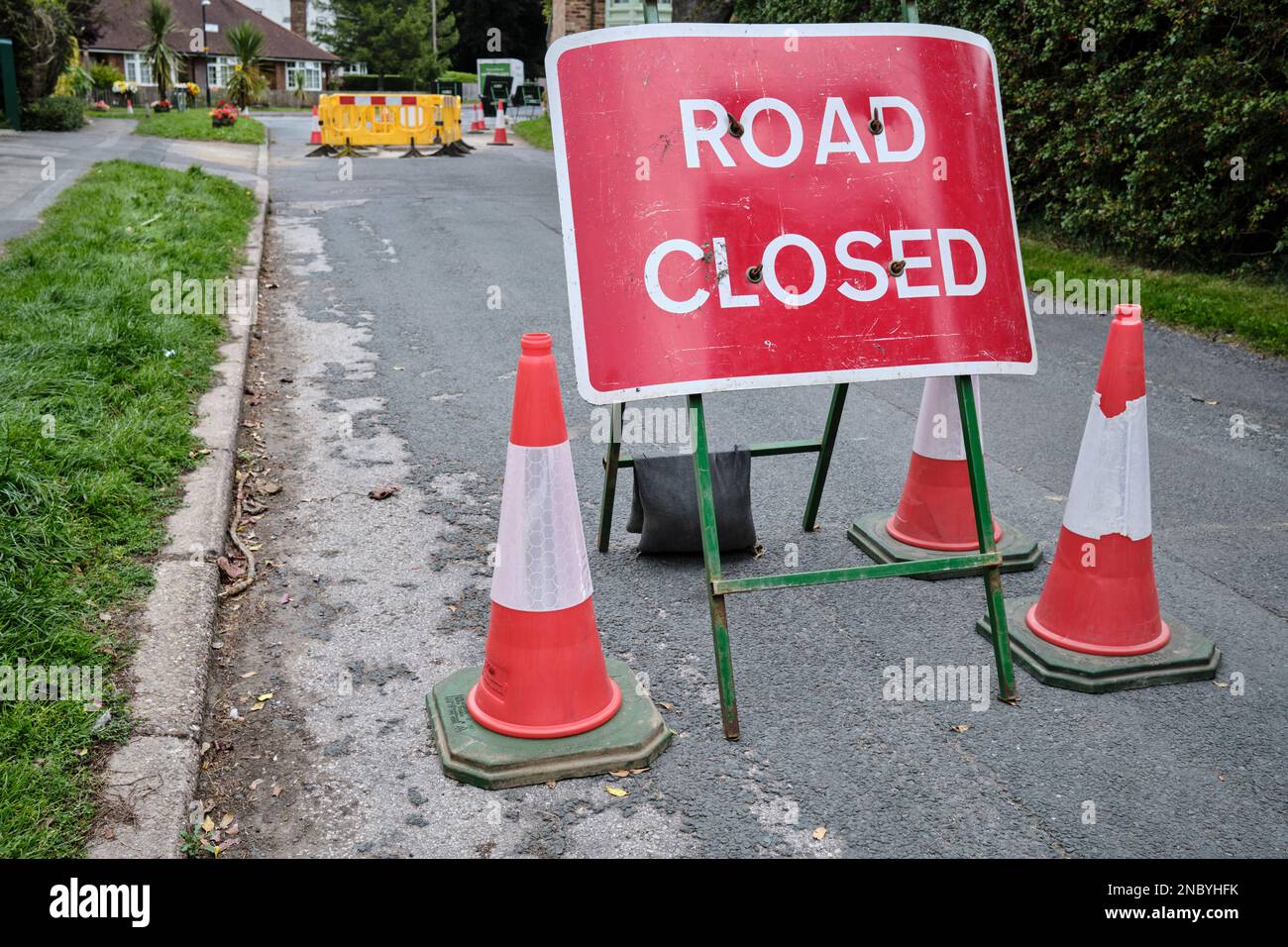 A road closed sign on a suburban British street. Yellow barriers ...