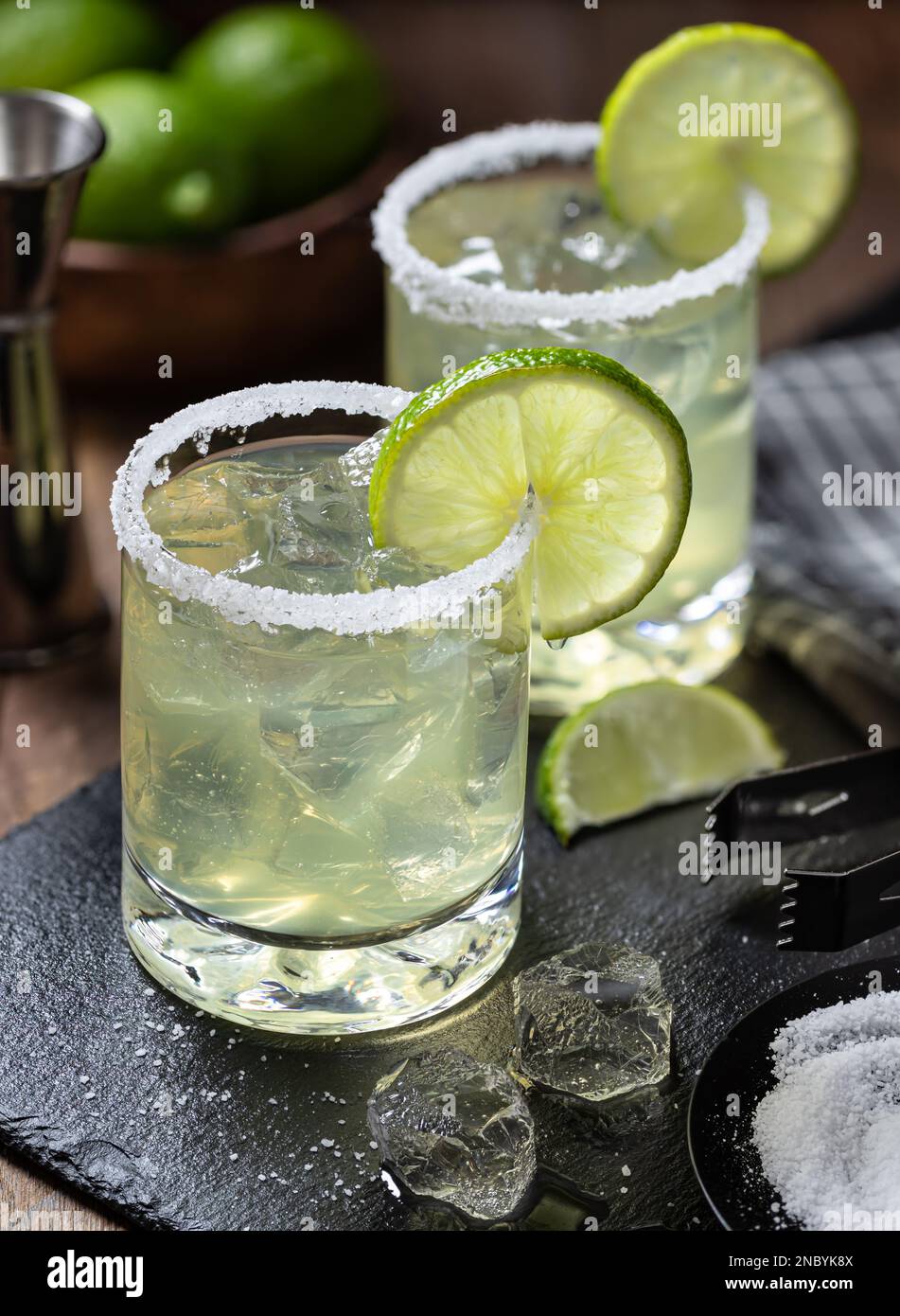 Margarita cocktail with ice, lime slice and salt rim on a black slate ...
