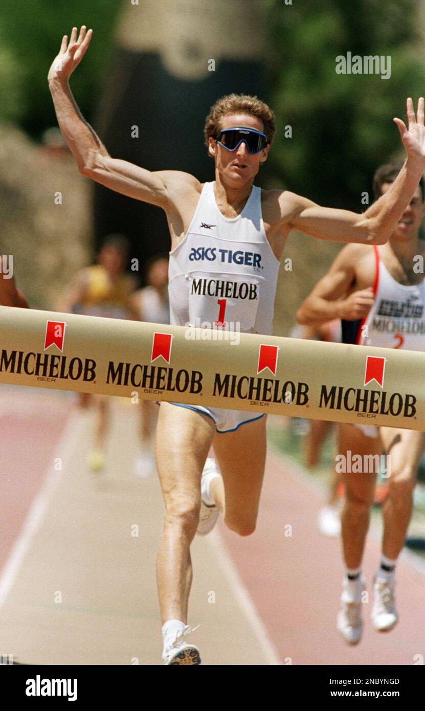 Miler Steve Scott raises his arms as breaks through the finish line ...