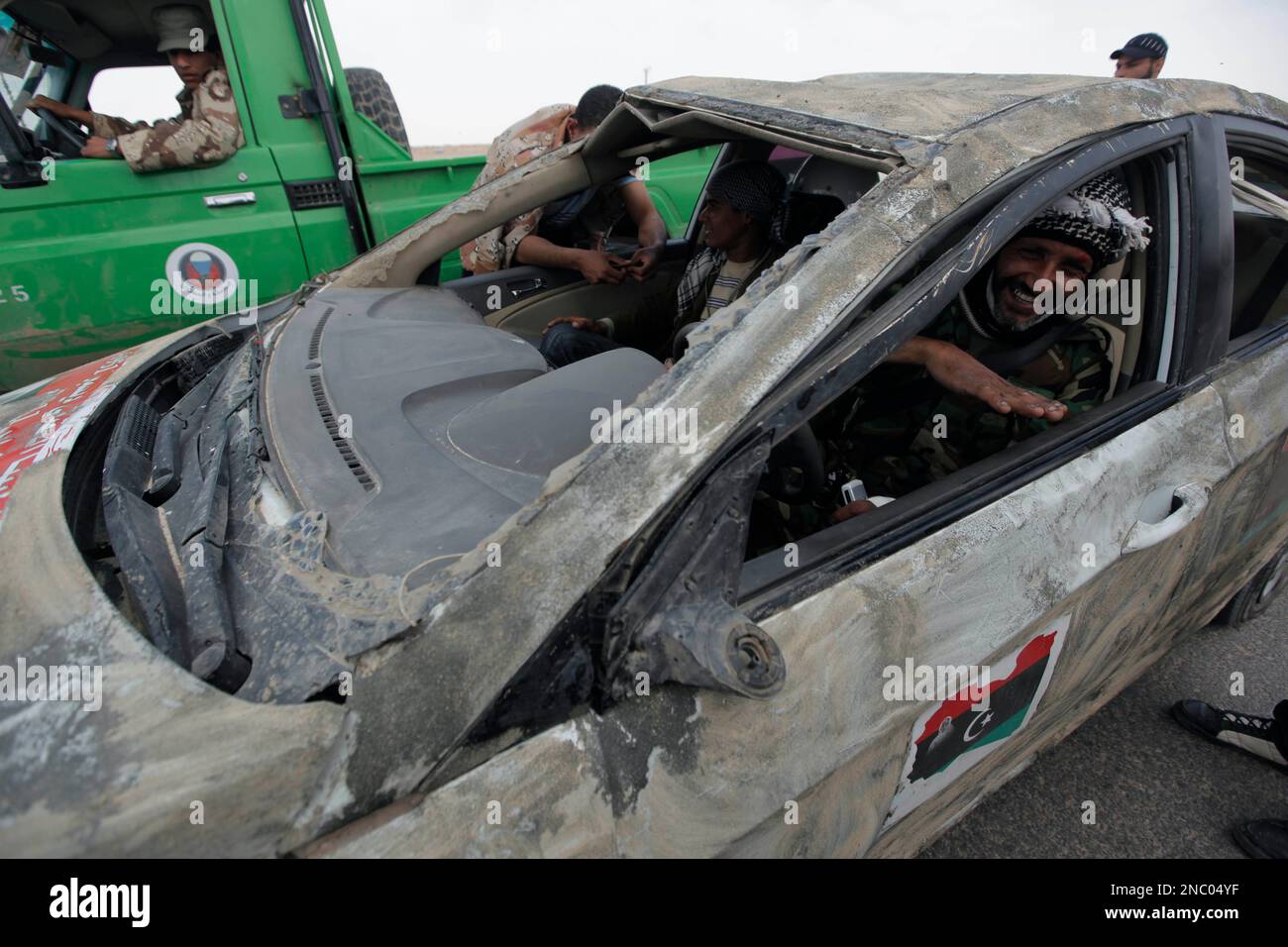 Two Libyan rebel fighters riding a shattered vehicle that was damaged ...