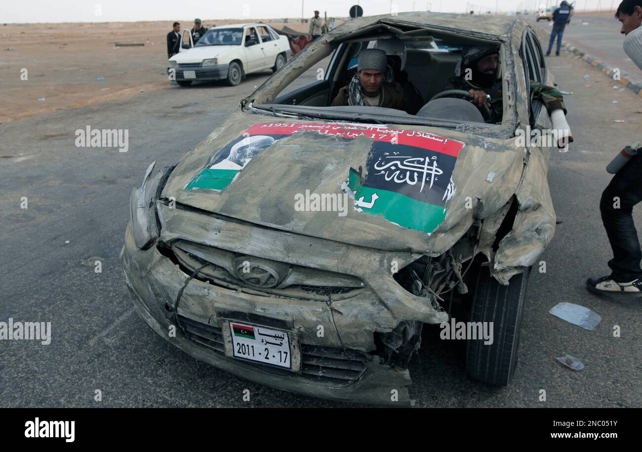 Two Libyan rebel fighters riding a shattered vehicle that was damaged ...