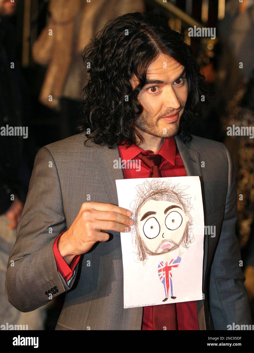 English comedian and actor Russell Brand holds a caricature drawing of ...