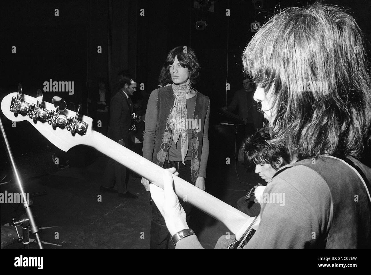 Rolling Stones lead singer Mick Jagger is framed by the guitar of bass ...