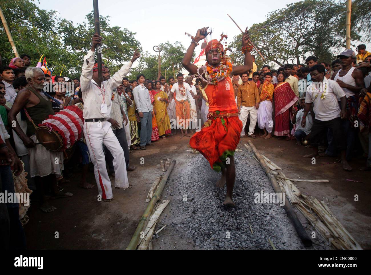 A Hindu devotee, his tongue pierced with iron rods, walks on burning ...