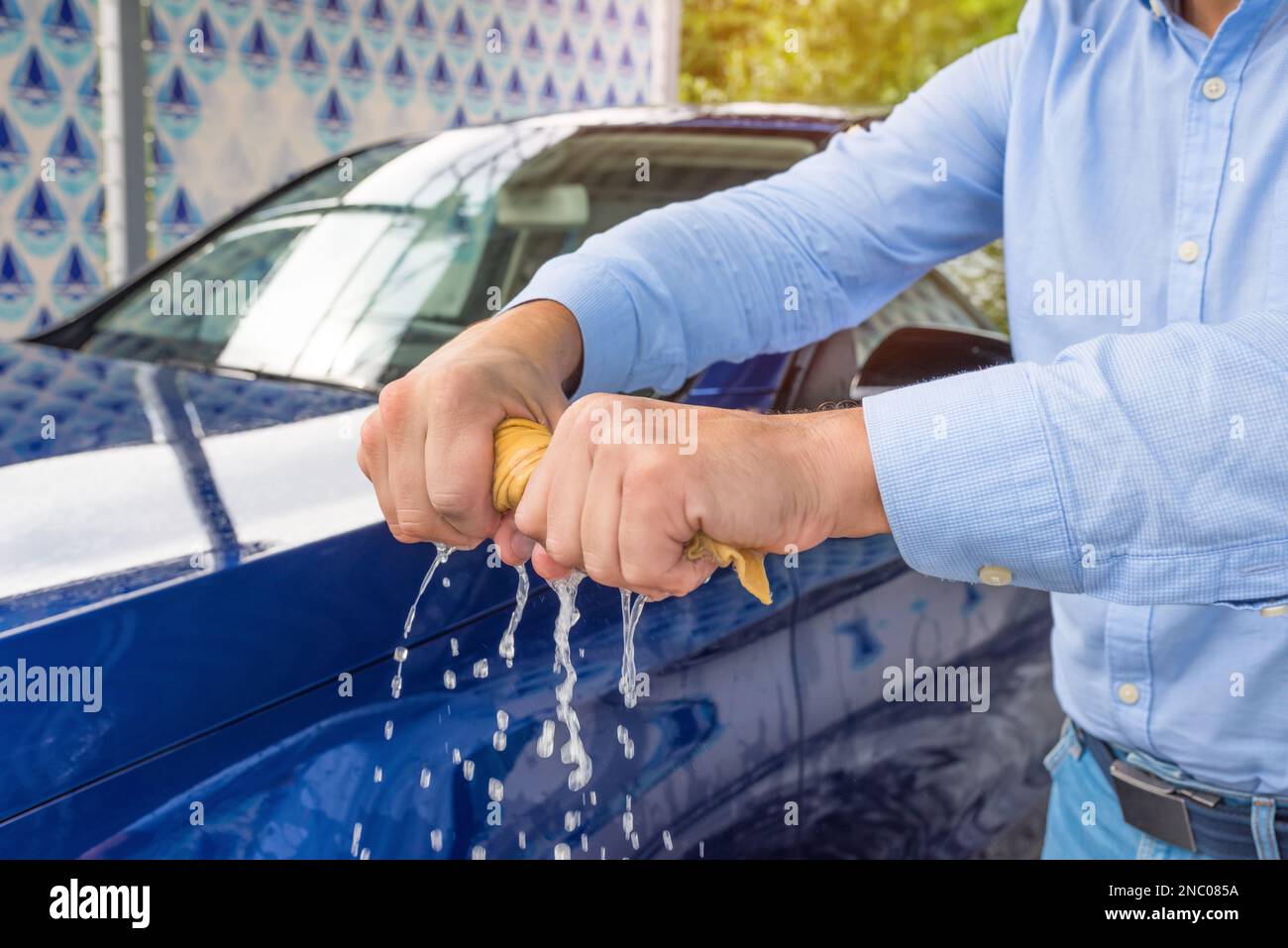 A mans hands are twisting a wet cloth at the car background Stock Photo ...