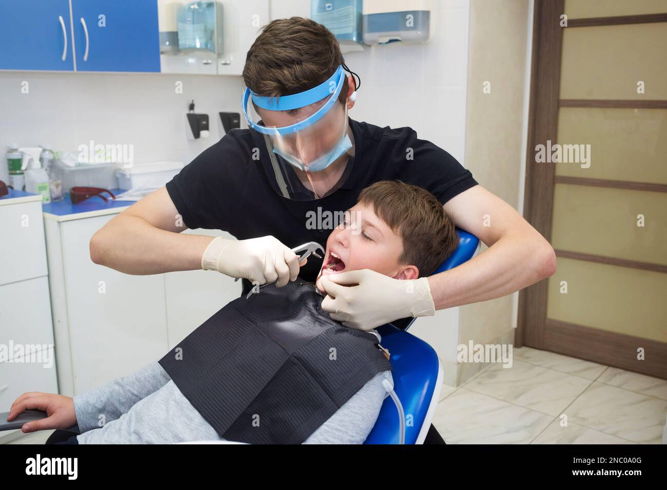A dentist pulling out a childs tooth with dental forceps Stock Photo ...
