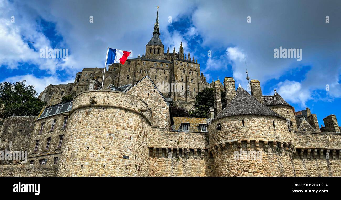 The Abbaye du Mont-Saint-Michel abbey with the French flag against blue ...