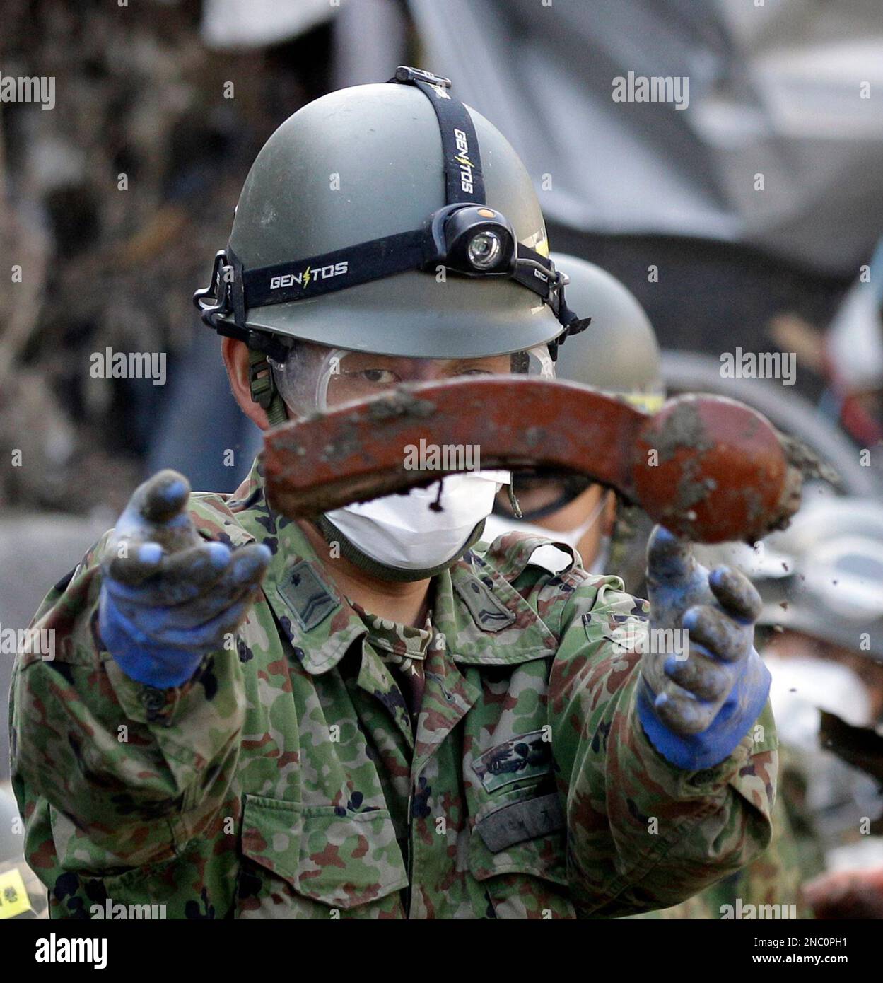 A member of Japan's Ground Self-Defense Force throws debris from a ...