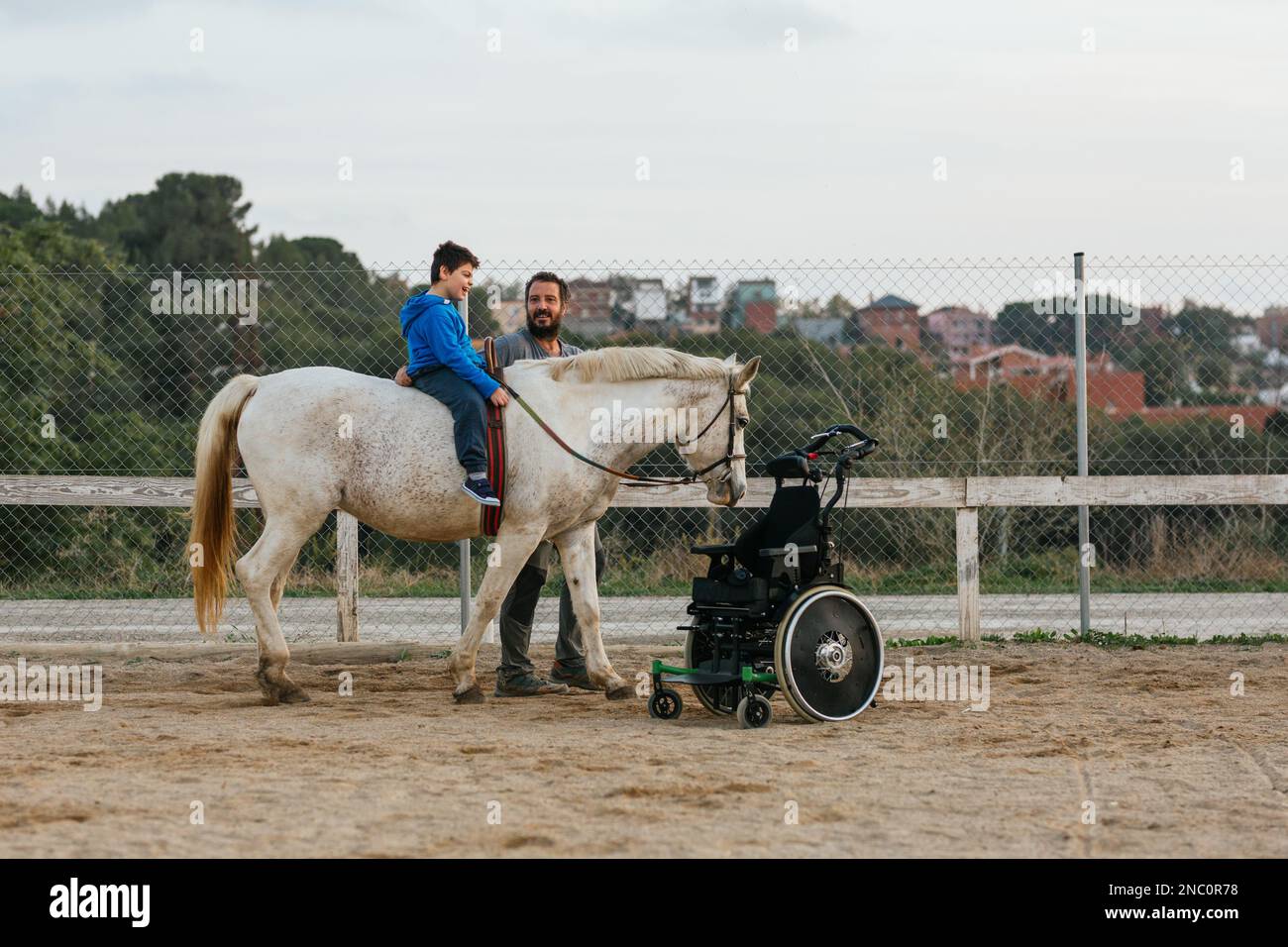 Boy with disabilities riding a horse while having an equine therapy ...