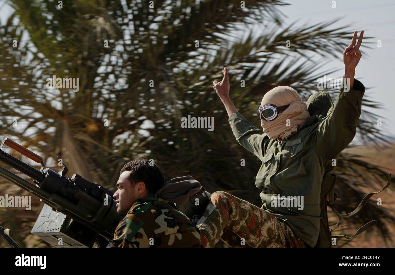 A rebel fighter riding on the back of a pickup truck mounted with an ...