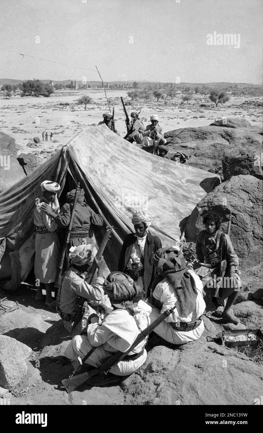 Ragged tribal guards surround the tent, pitched outside the village of ...