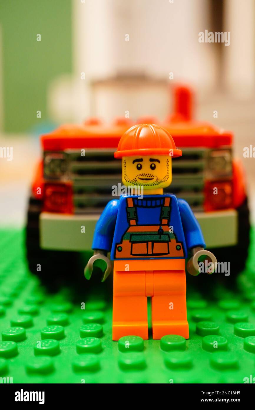 A lego construction worker with a red helmet near car with blurred ...