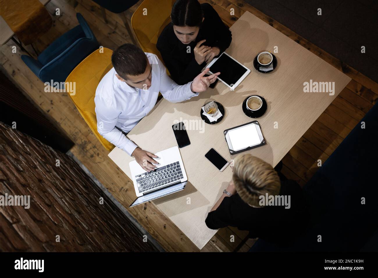 Three young business colleagues having a meeting in a modern cafe in ...