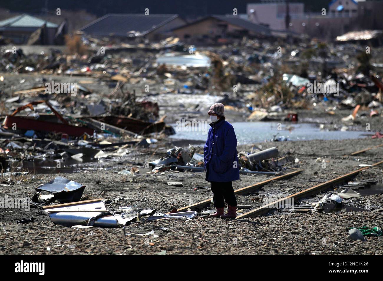 A woman walks in an area devastated by the March 11 tsunami to search ...
