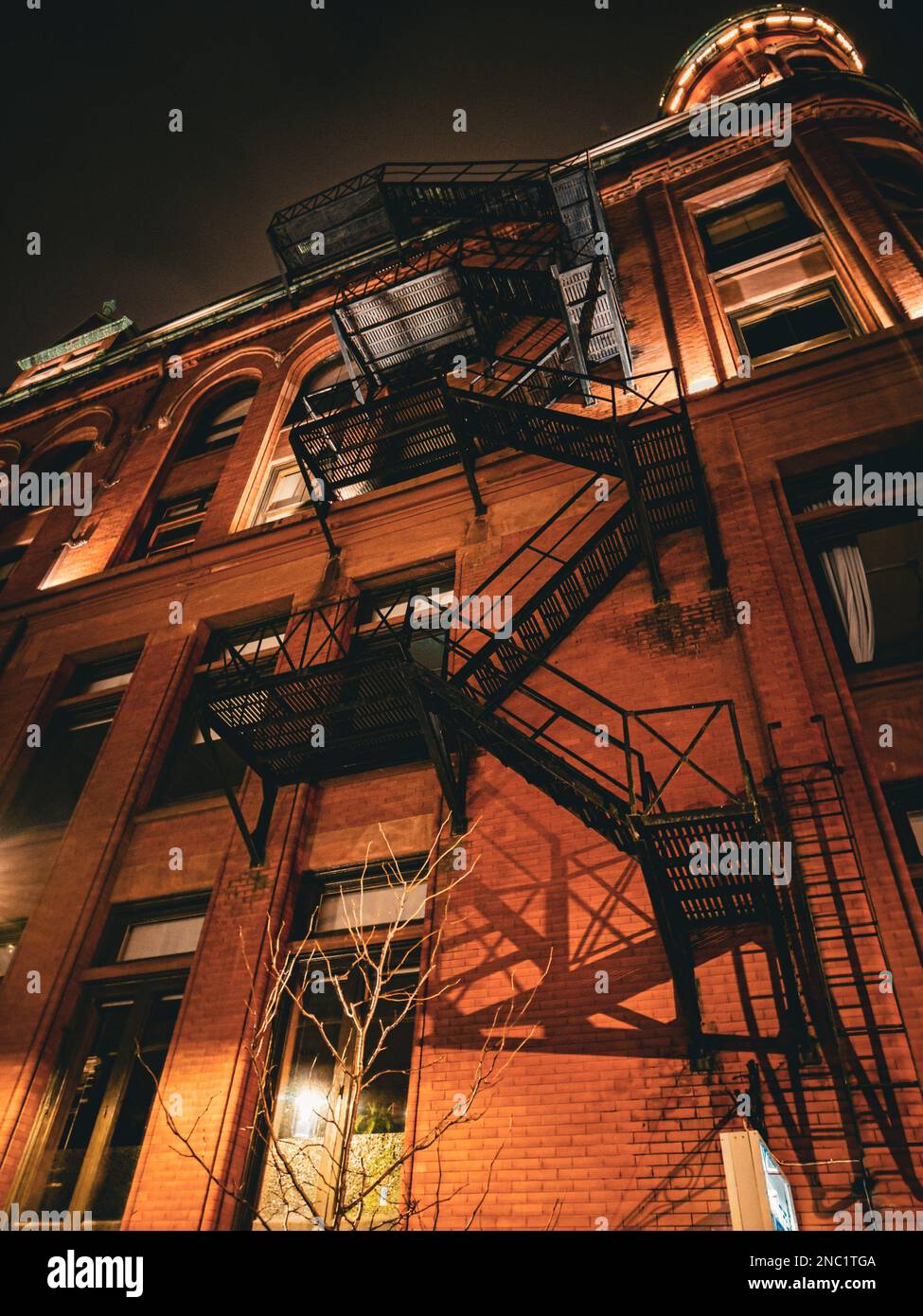 A vertical low-angle shot of a building with a fire escape at night ...