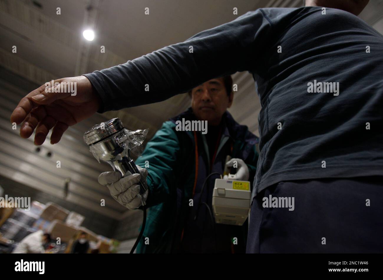 A man is screened for radiation contamination at an evacuation shelter ...