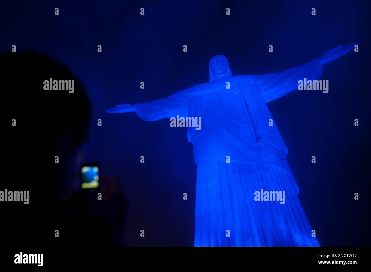A man photographs Christ the Redeemer statue illuminated in blue at ...