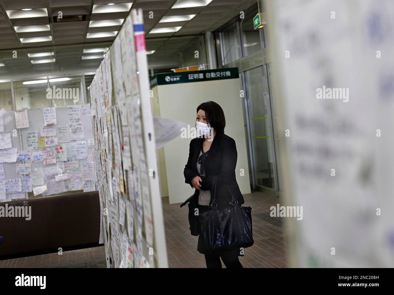 A woman scans a list of missing people at the city hall in the tsunami ...