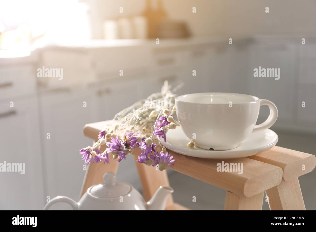 Decorative ladder with ceramic cup and flowers in kitchen, closeup ...