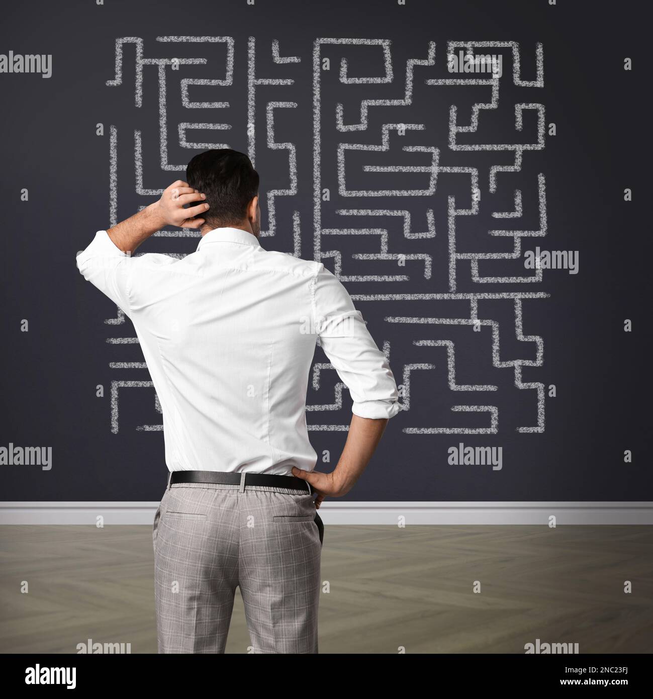 Businessman looking at wall with illustration of maze indoors Stock ...