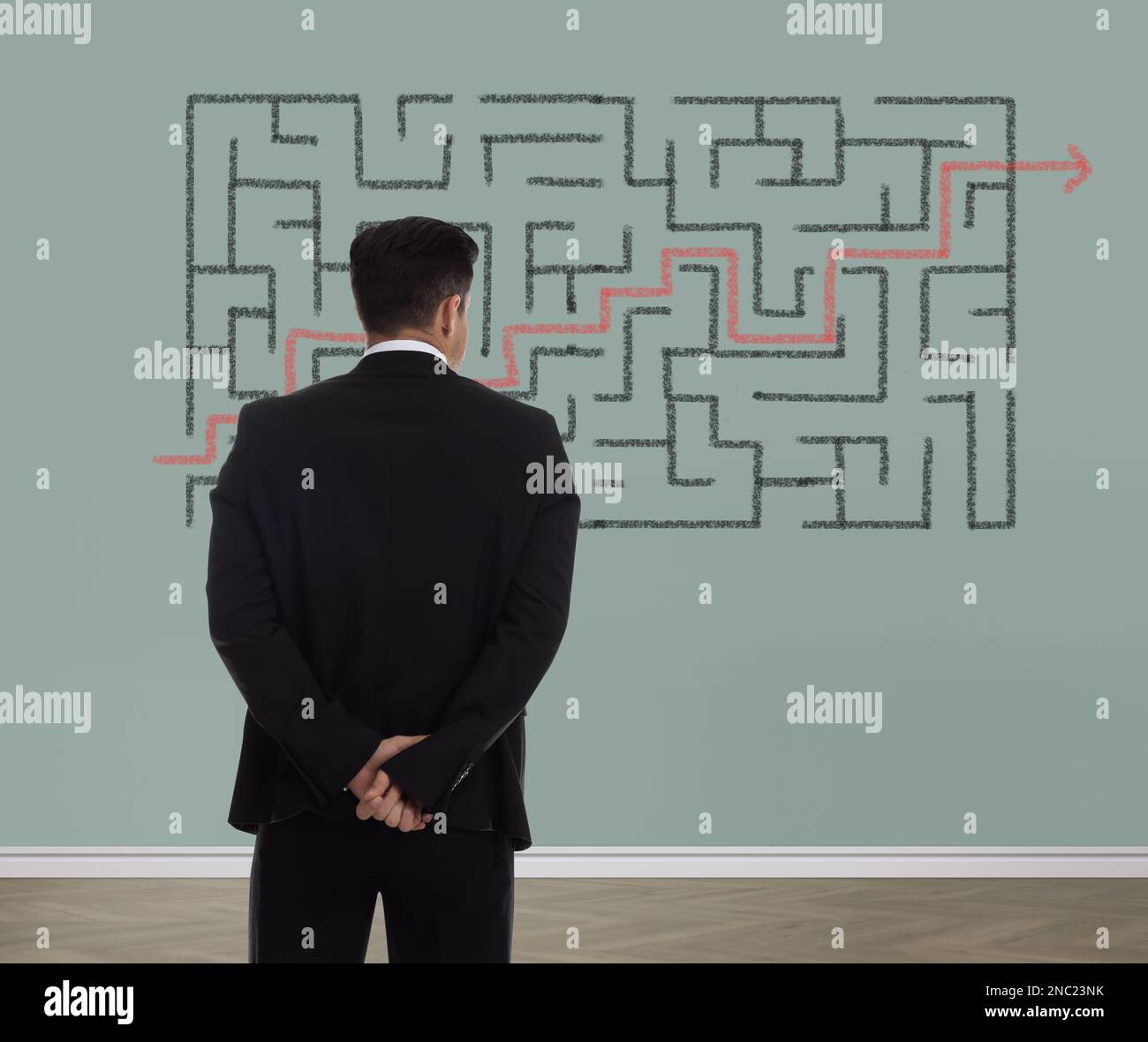Businessman looking at wall with illustration of maze indoors Stock ...