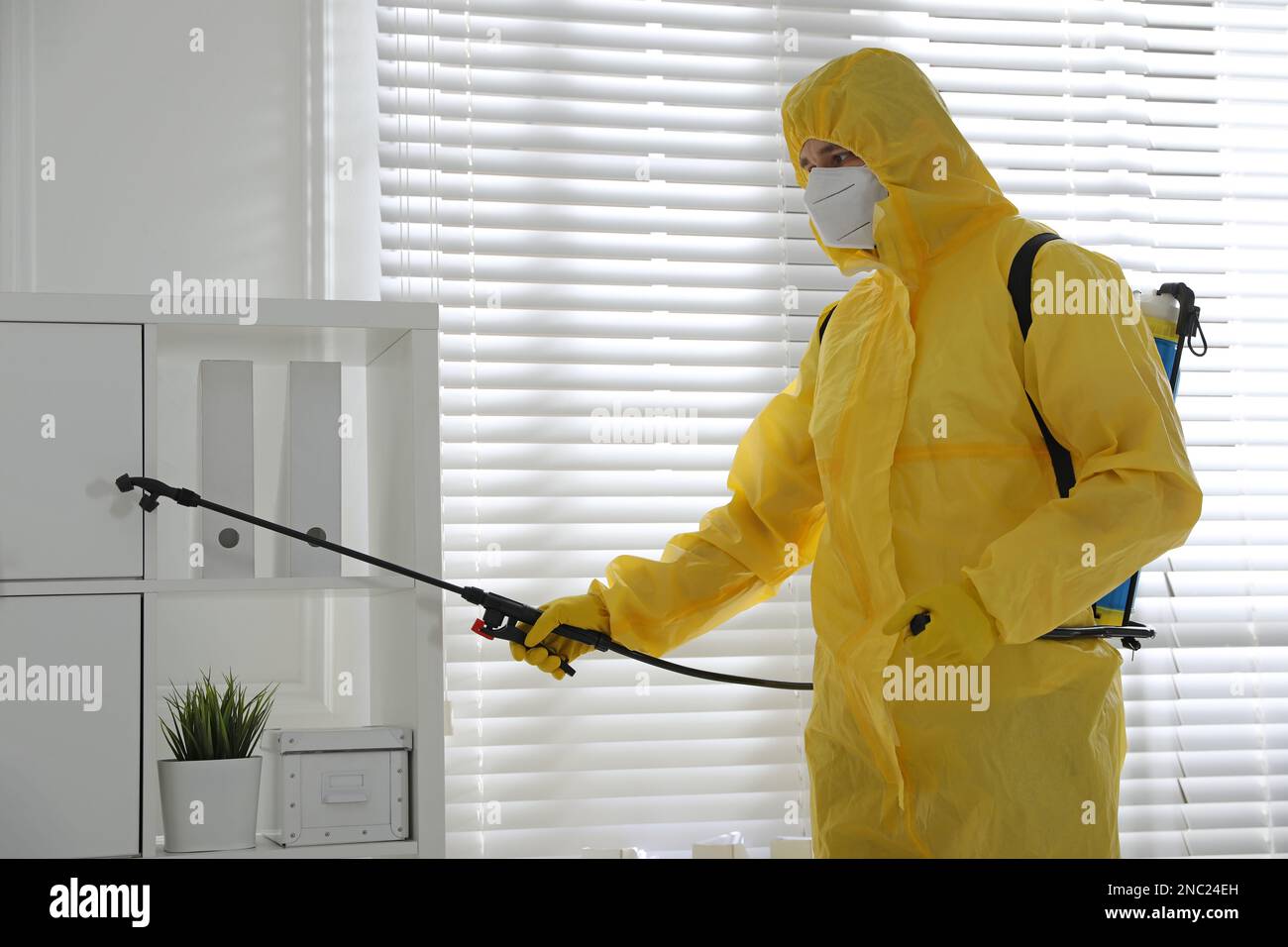 Man in protective suit sanitizing doctor's office. Medical disinfection ...