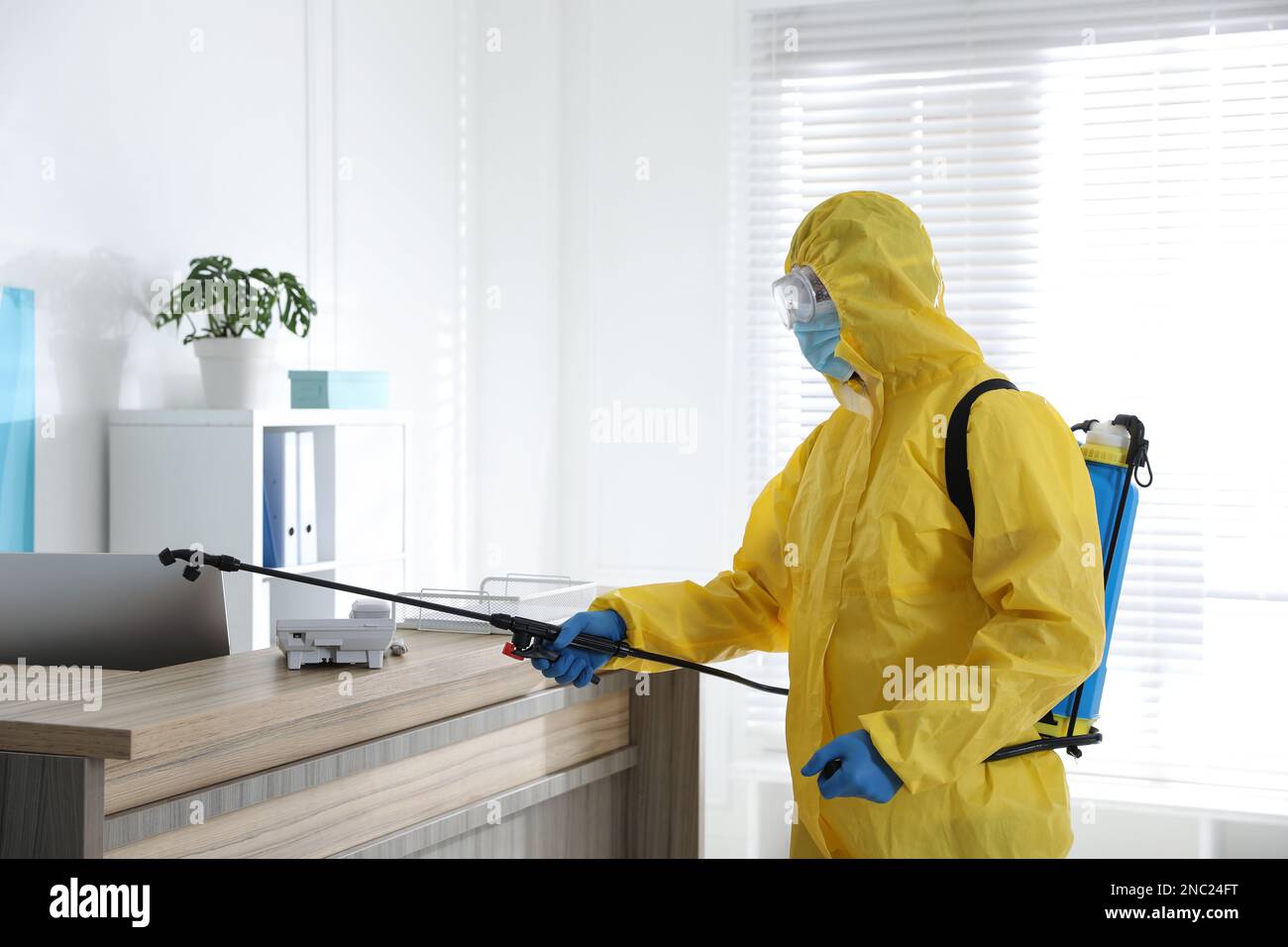 Employee in protective suit sanitizing office. Medical disinfection ...