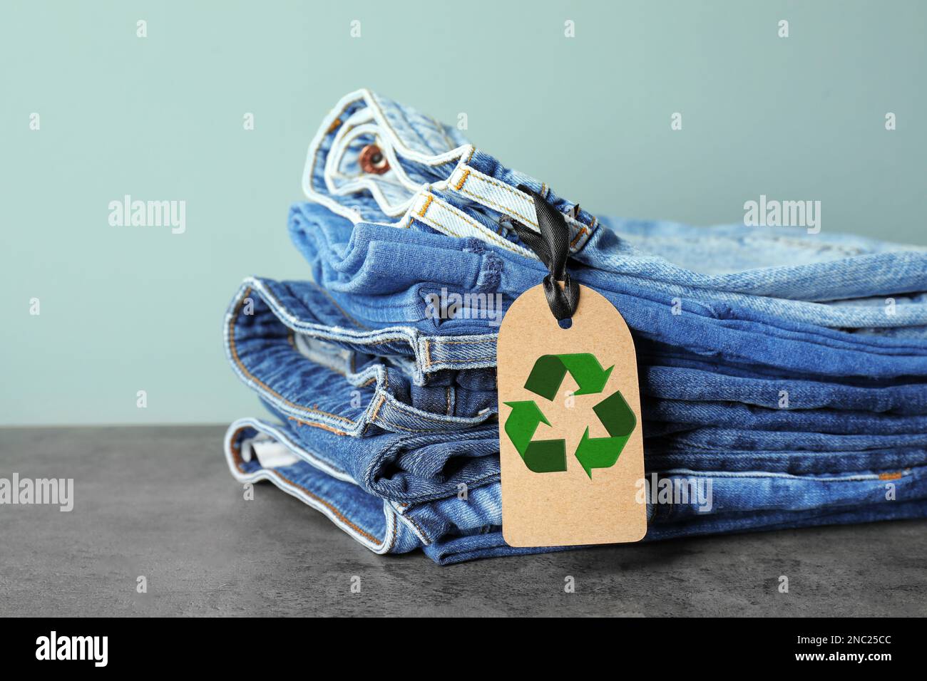 Stack of jeans with recycling label on grey table Stock Photo - Alamy