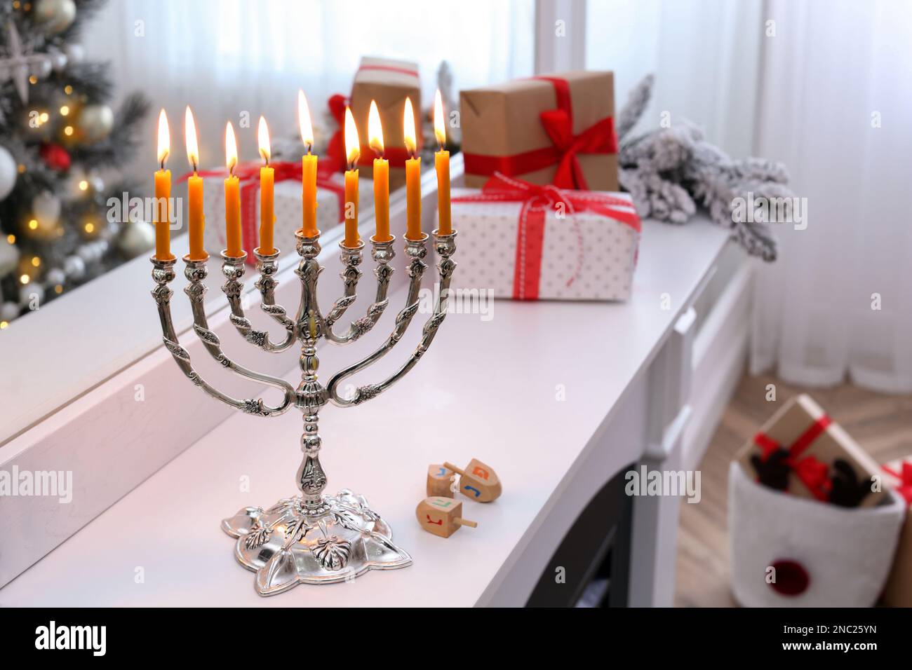 Silver menorah near dreidels with symbols He, Pe, Nun, Gimel on white ...