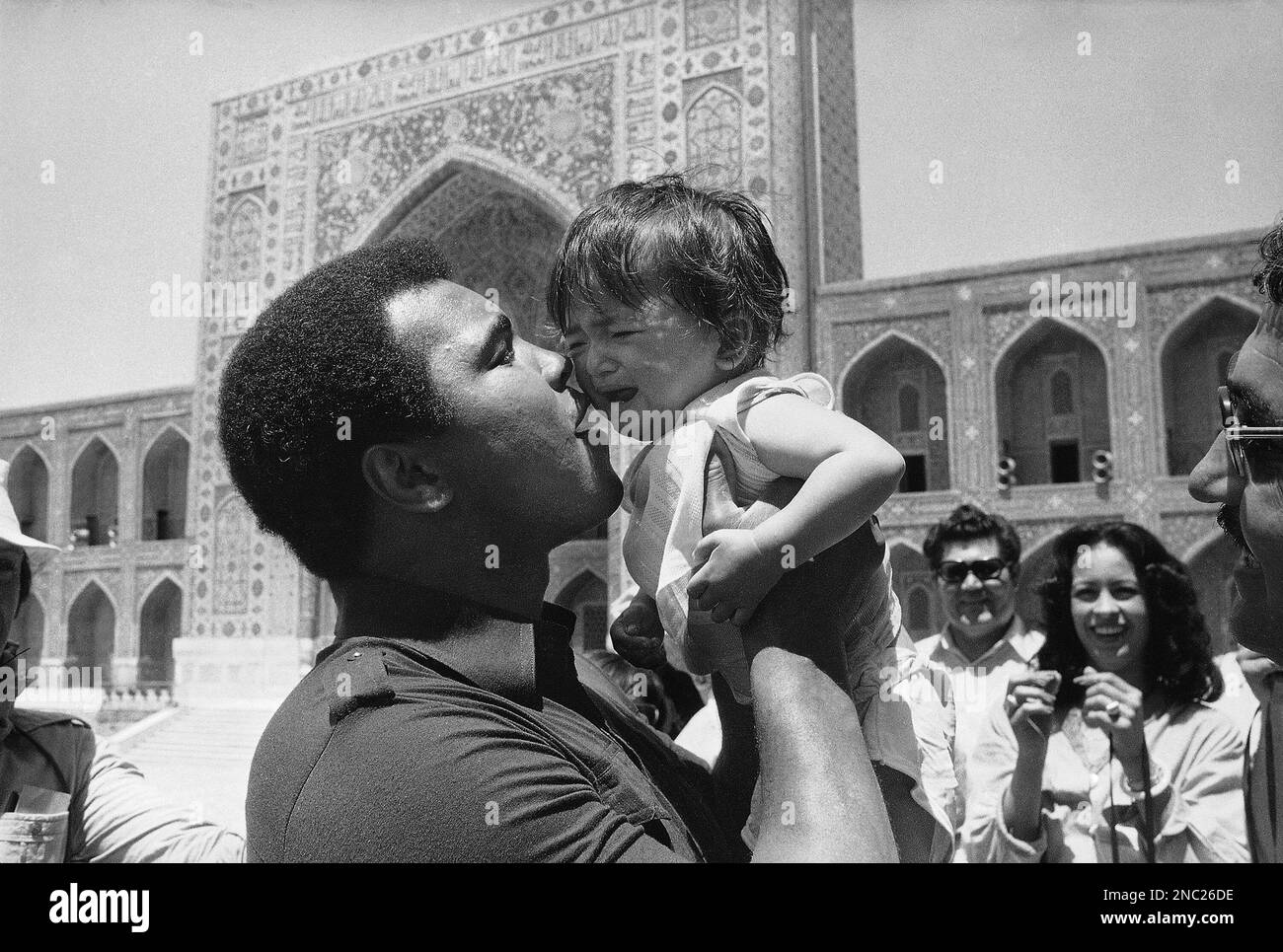Onlookers smile as U.S. boxer Muhammad Ali holds a crying child in ...