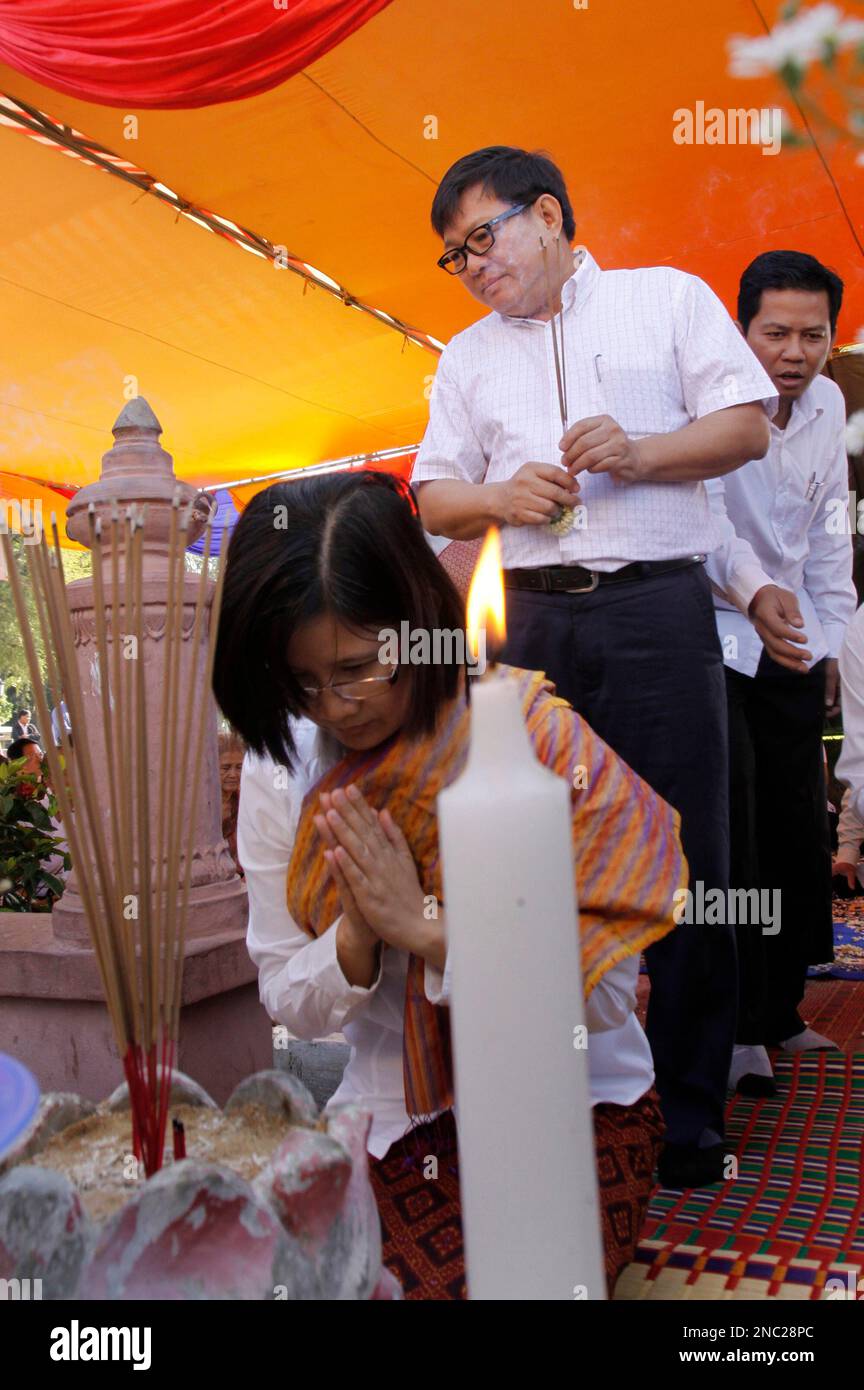 Cambodian lawmaker Sun Chhay, center, holds burned incense stick as he waits for praying in ...
